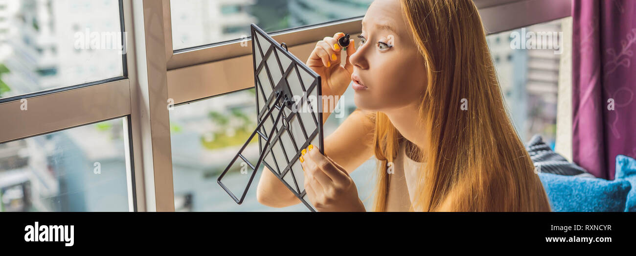 Young woman does makeup sitting by the window with a panoramic view of ...