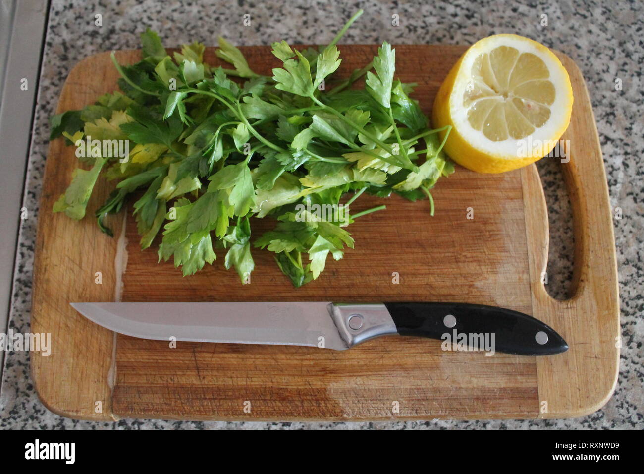 tuft of green garden parsley with lemon lay on kitchen board for ...