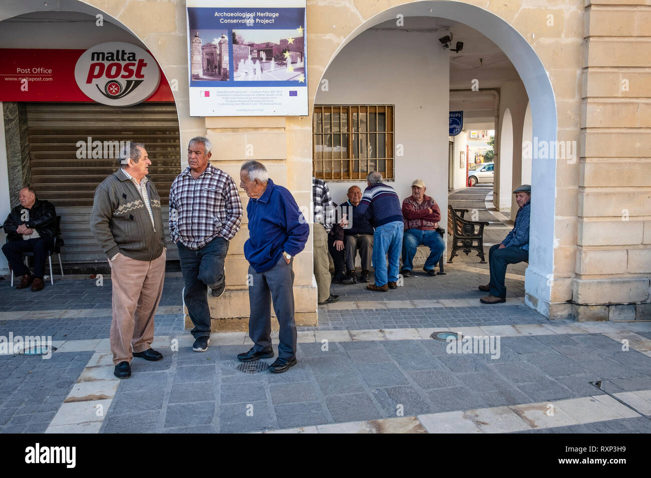 Old men gather outside the post office in the town square to chat ...