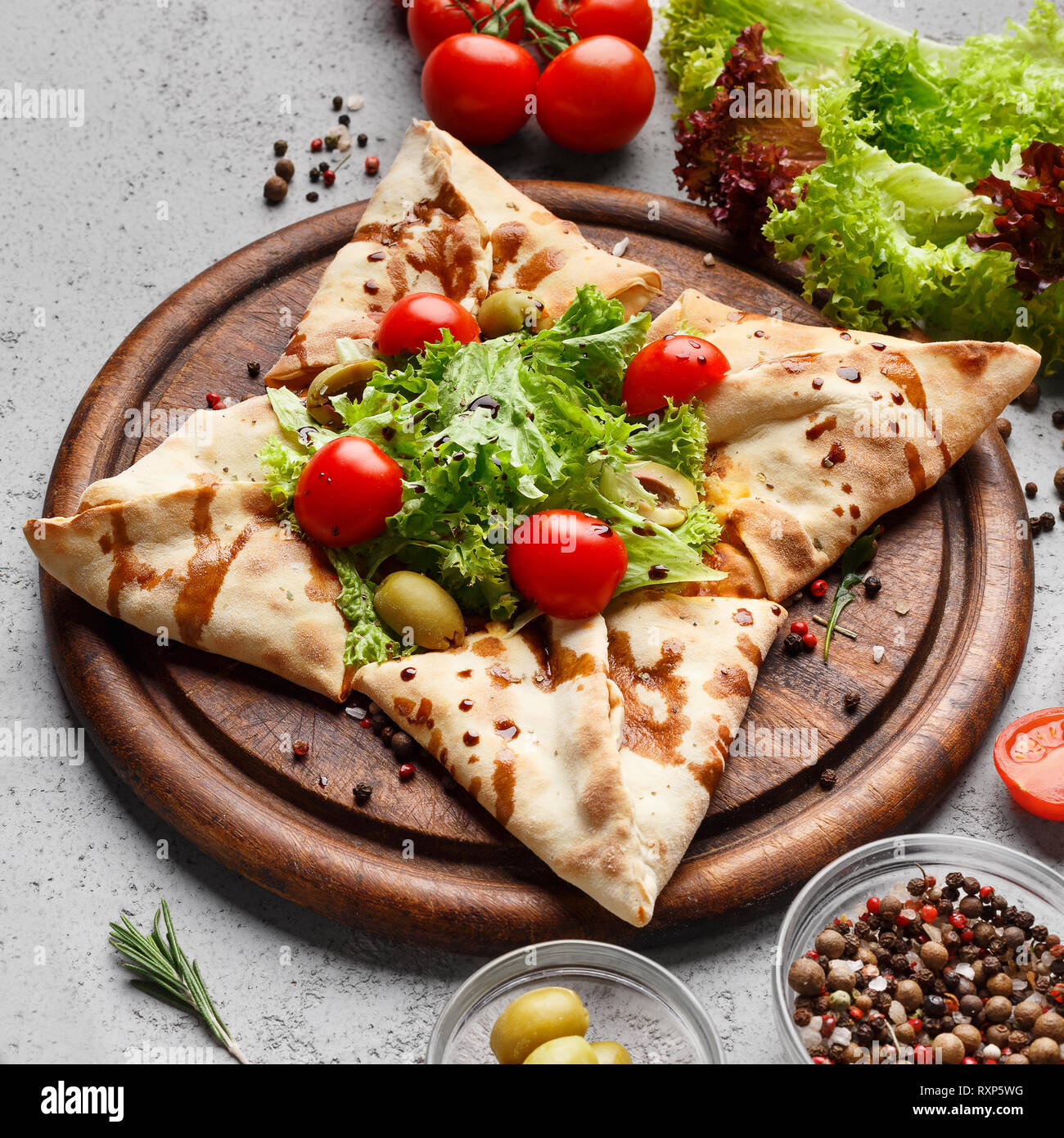 Closed star shaped pizza decorated with lettuce and cherry tomatoes ...