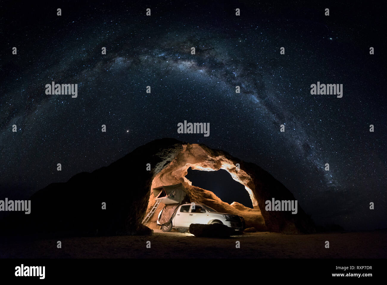A Camping 4x4 inside a rock arch in Namibia under the milky way bow ...