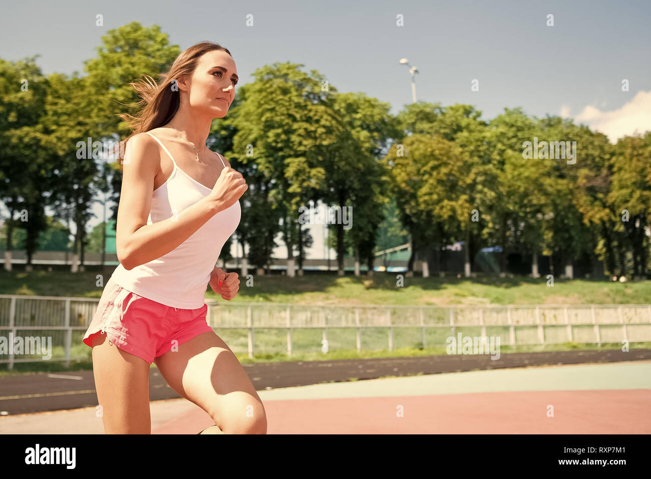 Runner on competition and future success. Girl sunny outdoor on blue ...