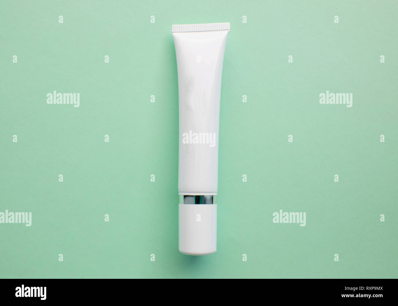 White plastic cream tube with space for text on a light green ...