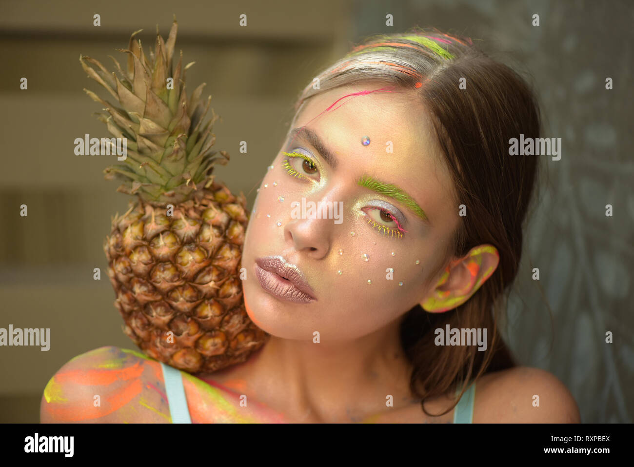 Pineapple on girl shoulder on colors festival Stock Photo - Alamy