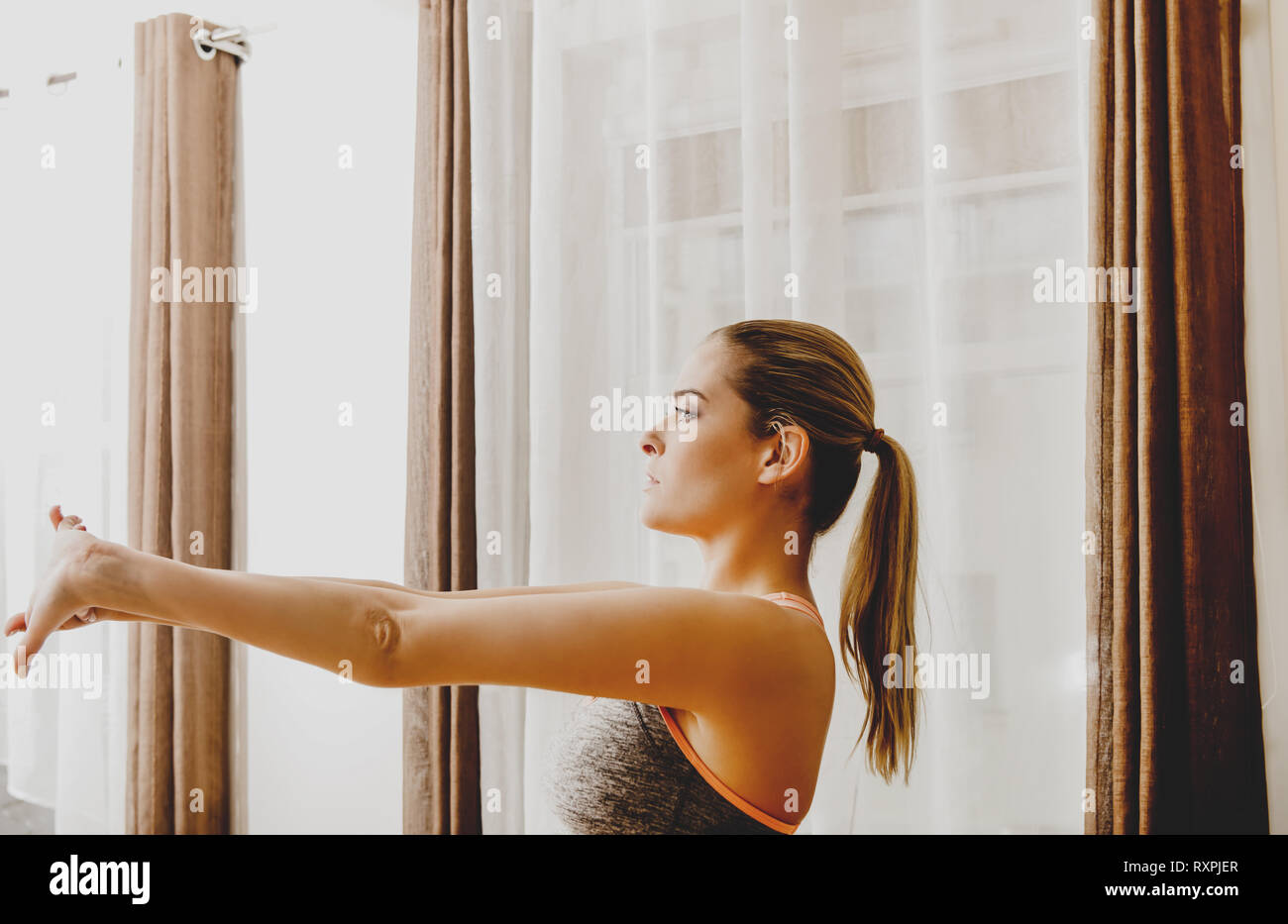 Young woman is stretching out near window in home. Fitness lifestyle ...