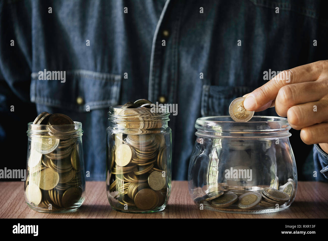 Hand putting money coin in the glass jar. Saving money, financial and ...