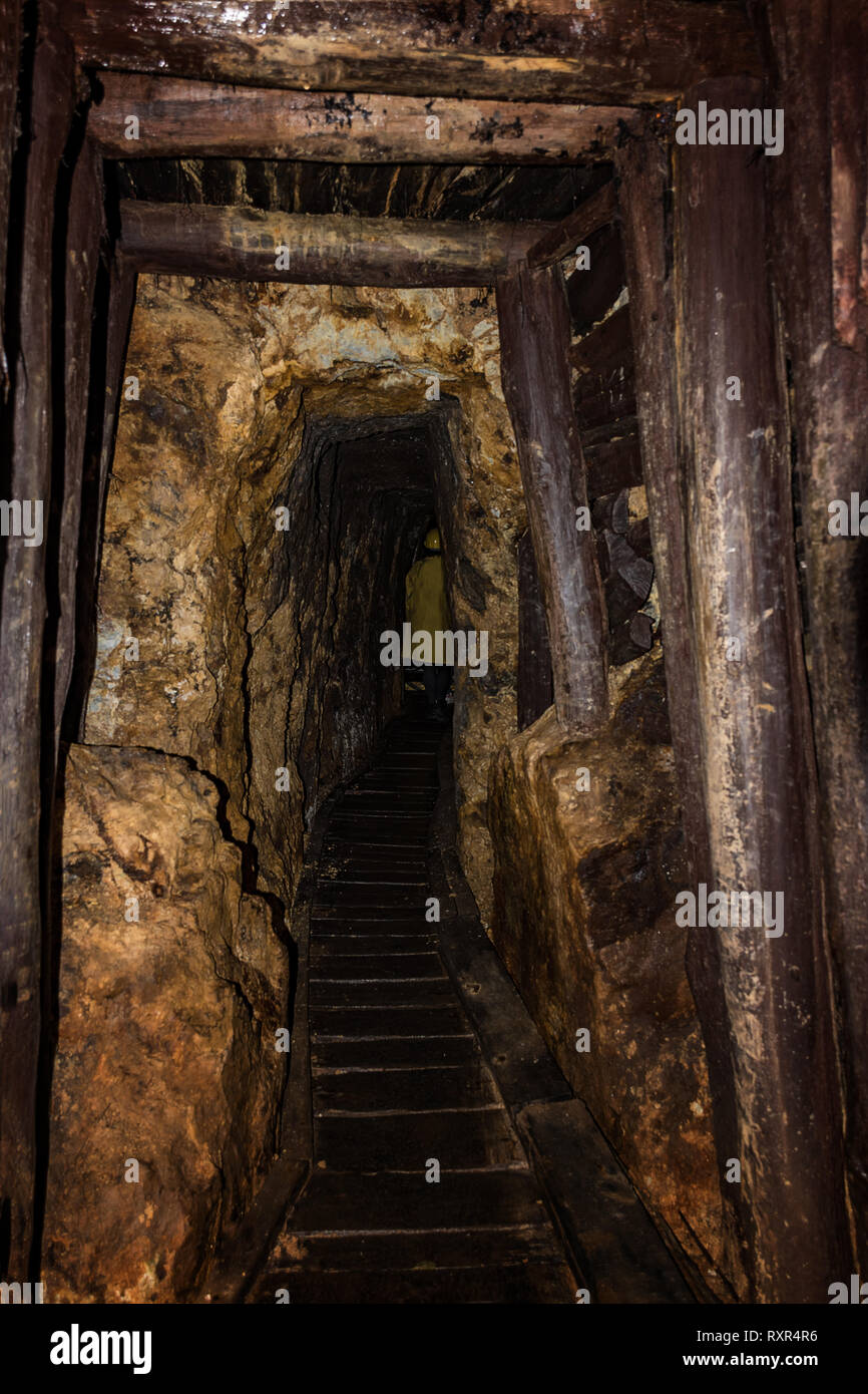 Old mine shaft with wooden timbering and person dressed in a mining ...