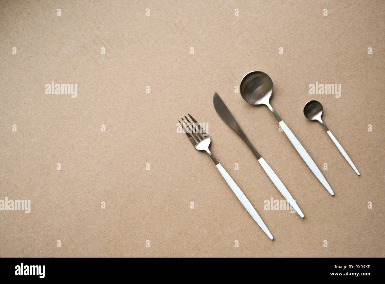Set of stylish white and chrome cutlery on beige background, top view ...