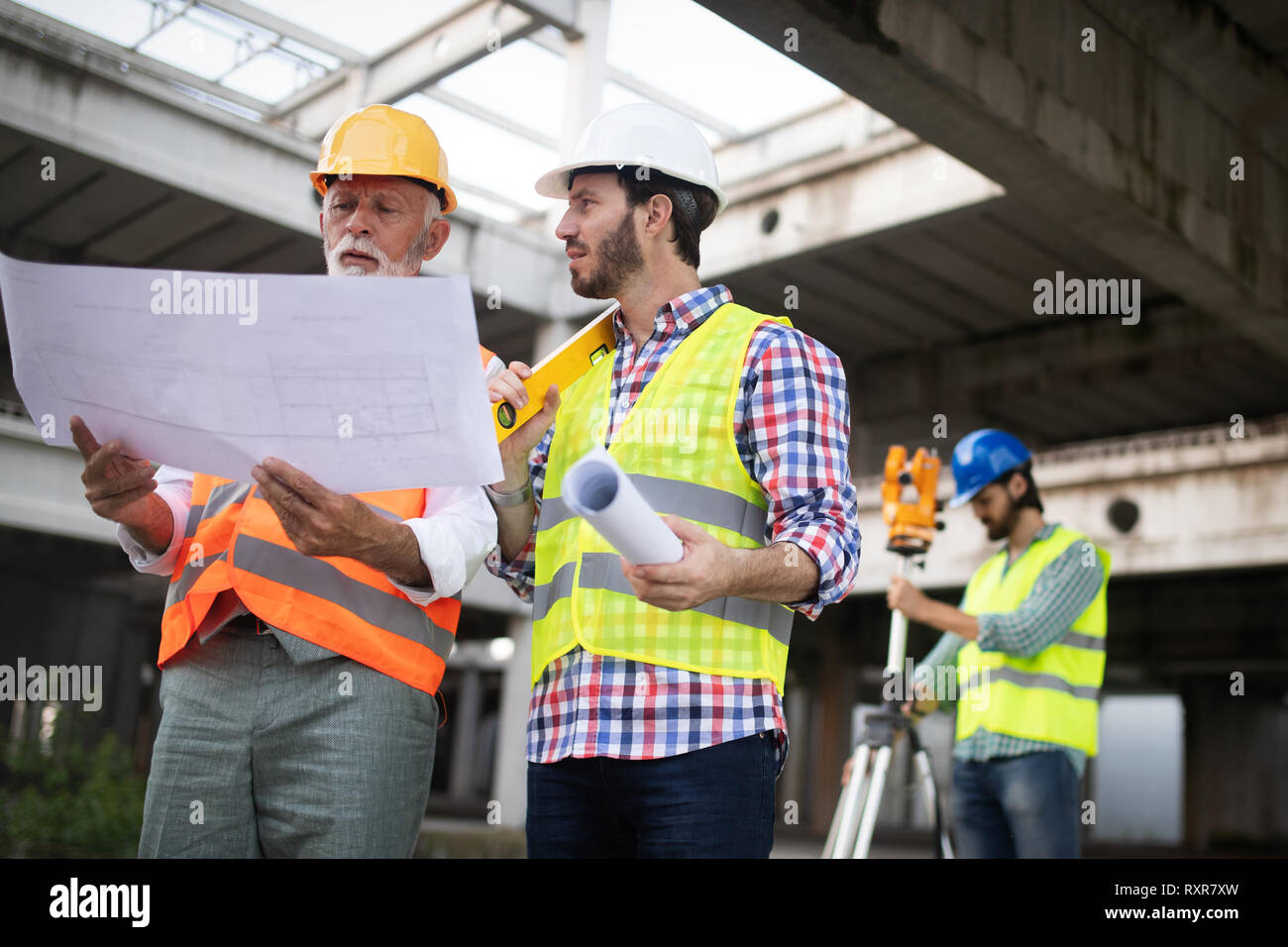 Engineer, foreman and worker discussing in building construction site ...