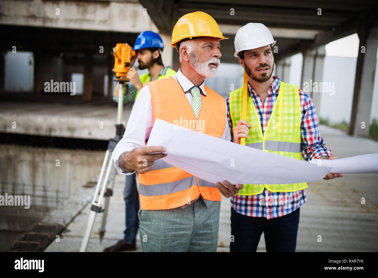 Engineer, foreman and worker discussing in building construction site ...