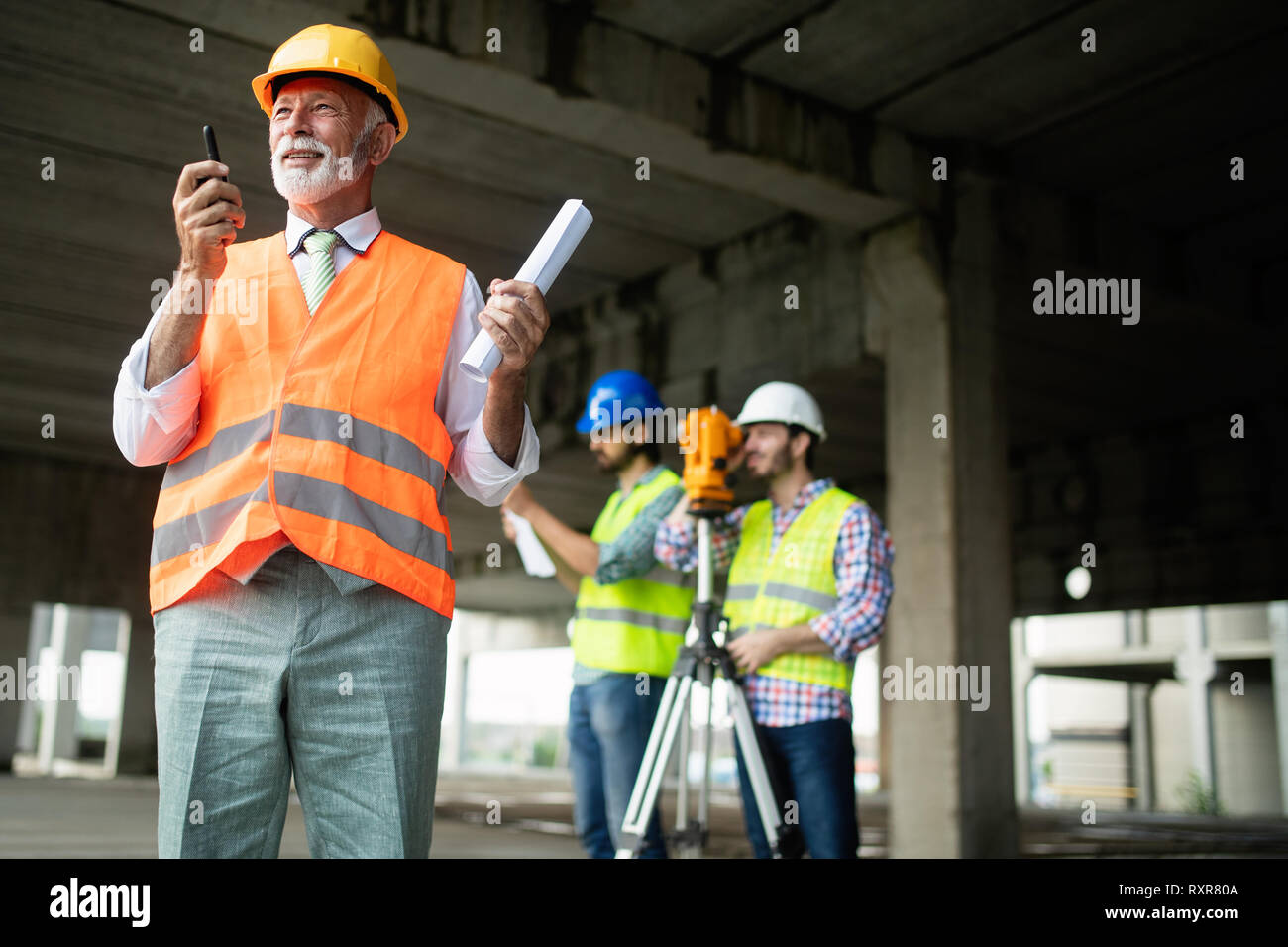 Engineer, foreman and worker discussing in building construction site ...