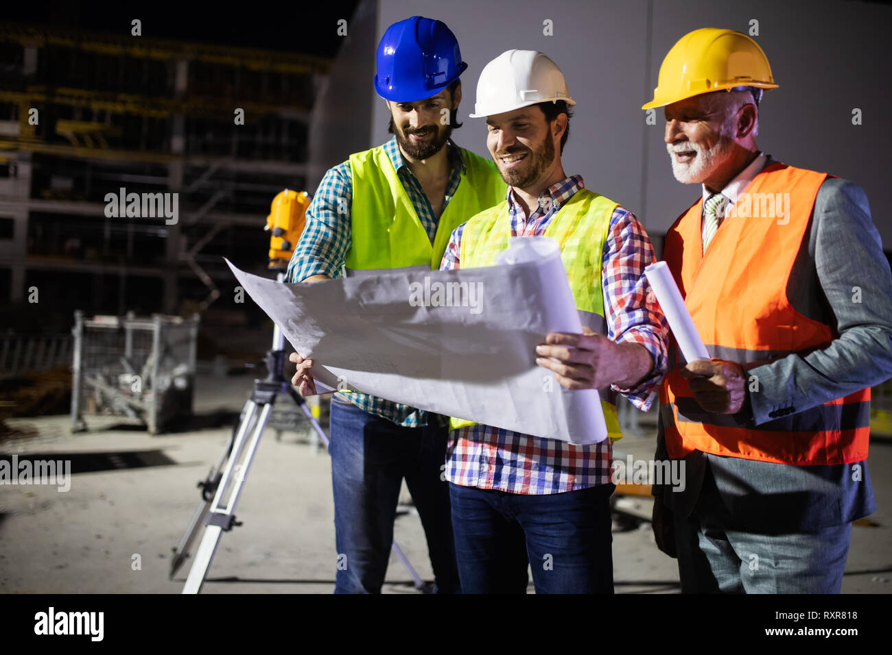 Engineer, foreman and worker discussing in building construction site ...