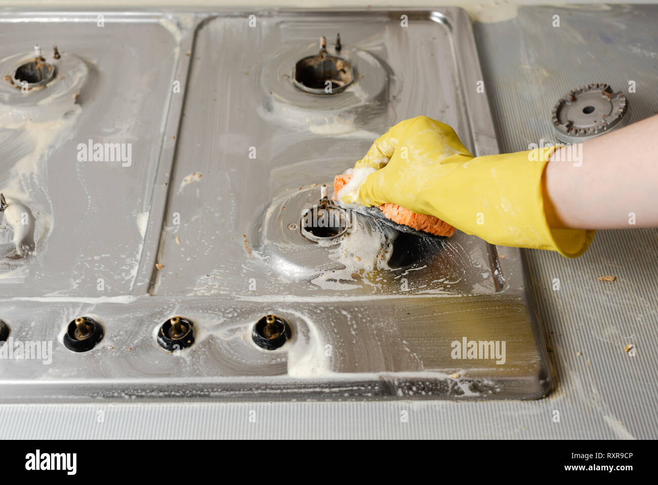 Hand in yellow rubber glove wash gas stove burner Stock Photo - Alamy