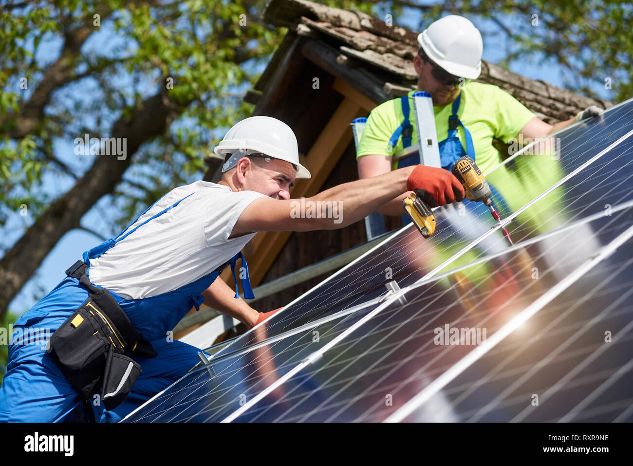 Two workers technicians installing heavy solar photo voltaic panels to ...