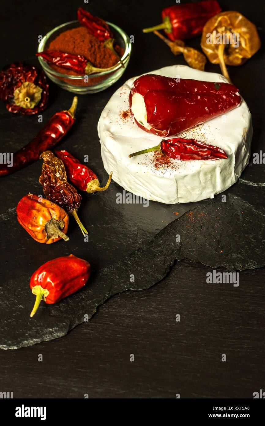 Moldy cheese and peppers on a black background. Dried chili peppers ...