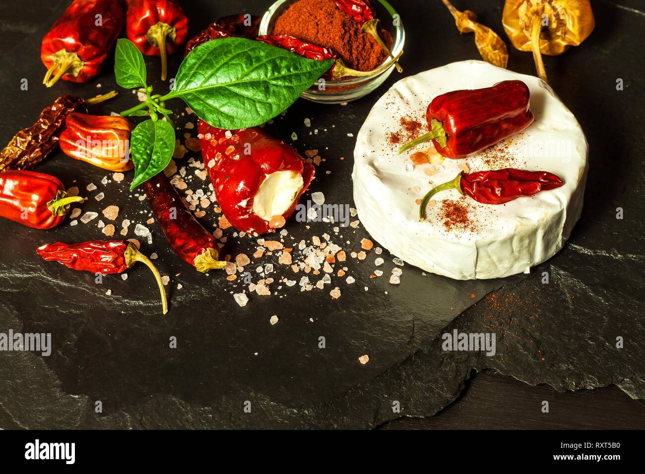 Moldy cheese and peppers on a black background. Dried chili peppers ...