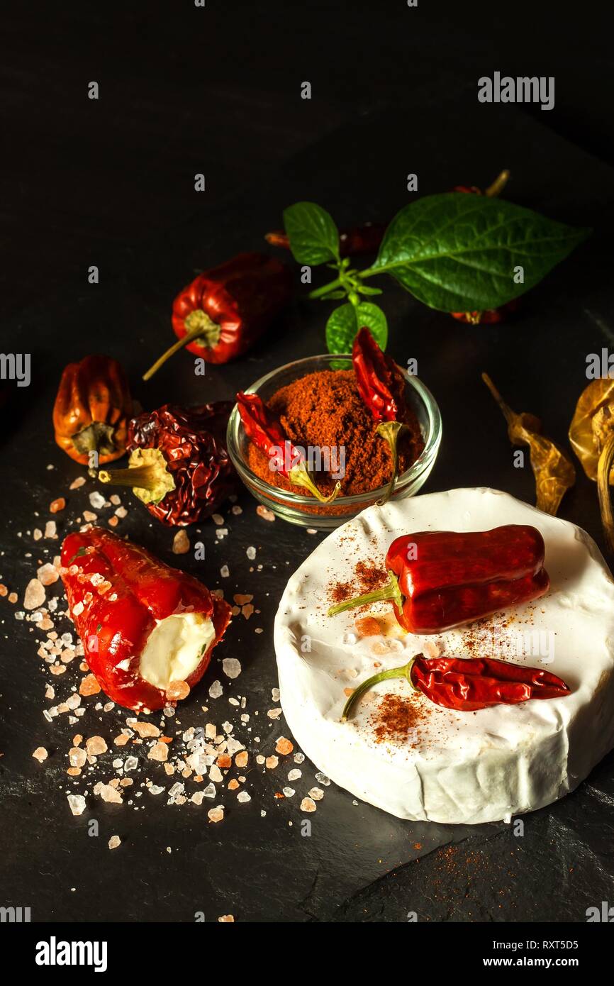 Moldy cheese and peppers on a black background. Dried chili peppers ...