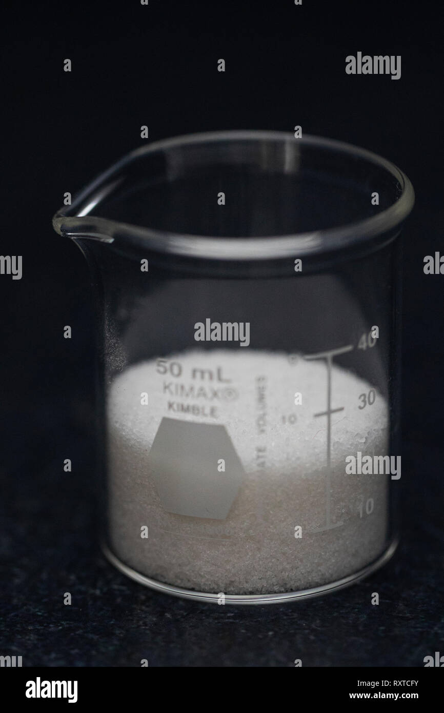 Sugar crystals in a beaker on a dark background Stock Photo - Alamy