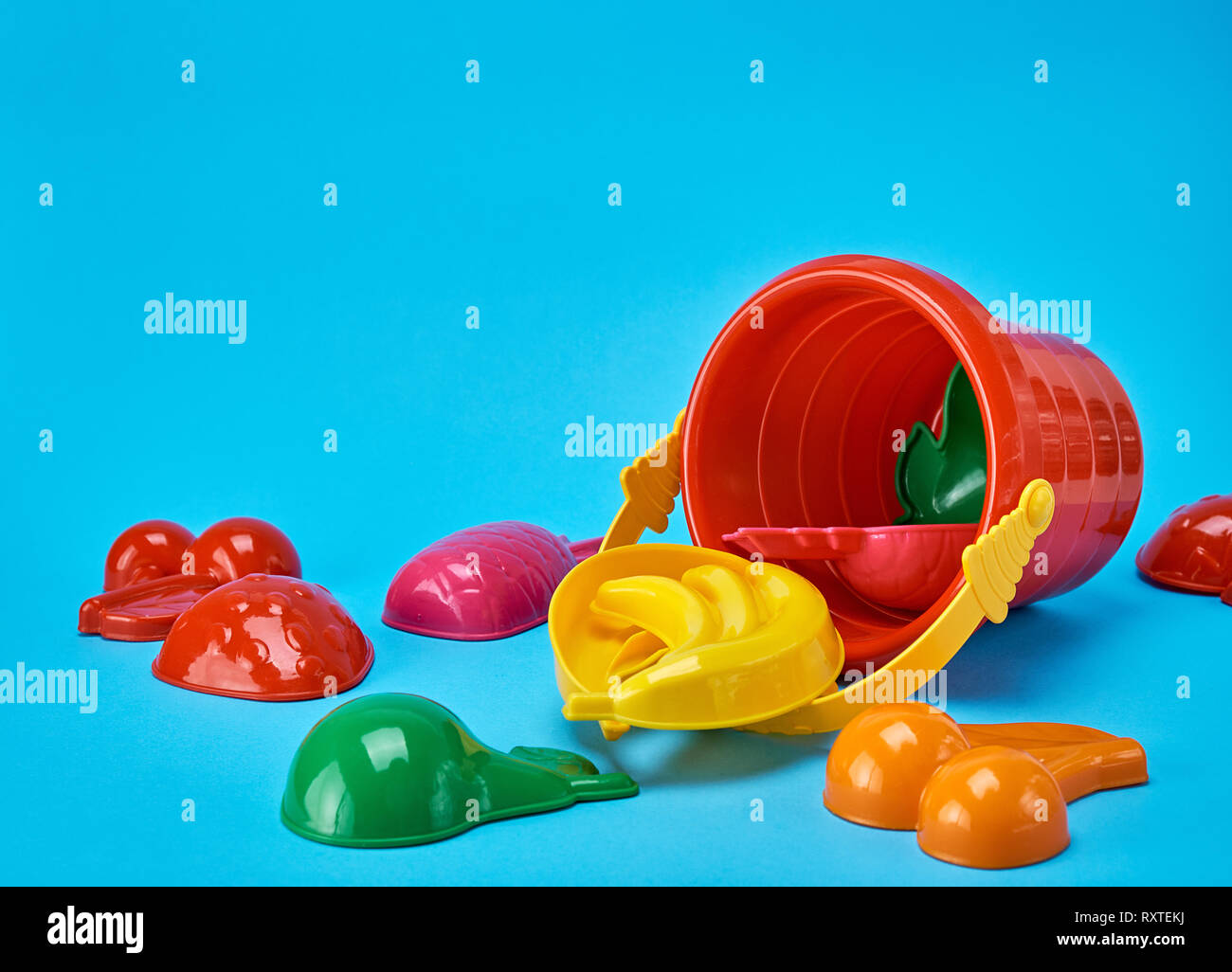 baby plastic red bucket and other items to play on a blue background ...