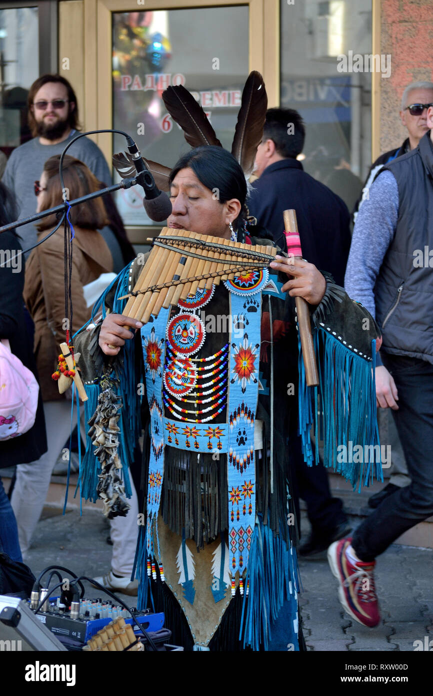 Female, indigenous,South American, street performer playing pan flute ...