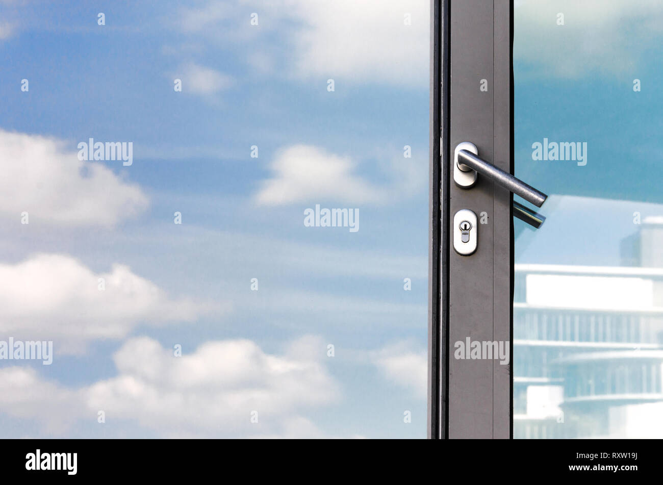 reflection of the cloudy sky in the glass of the entrance door of the ...