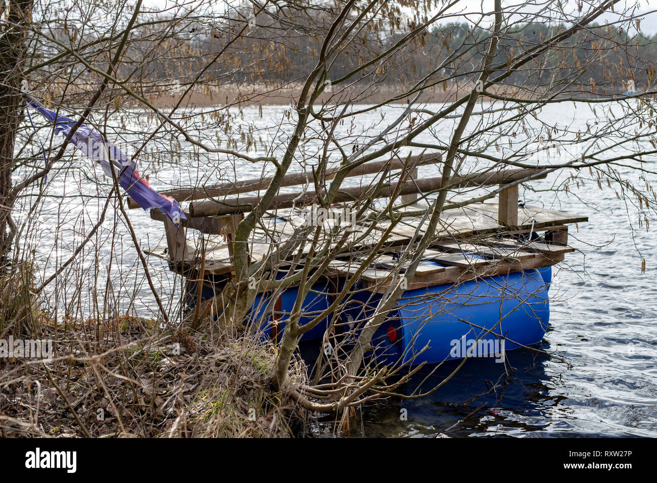 A raft built on blue barrels. A watercraft on the shore of the lake ...