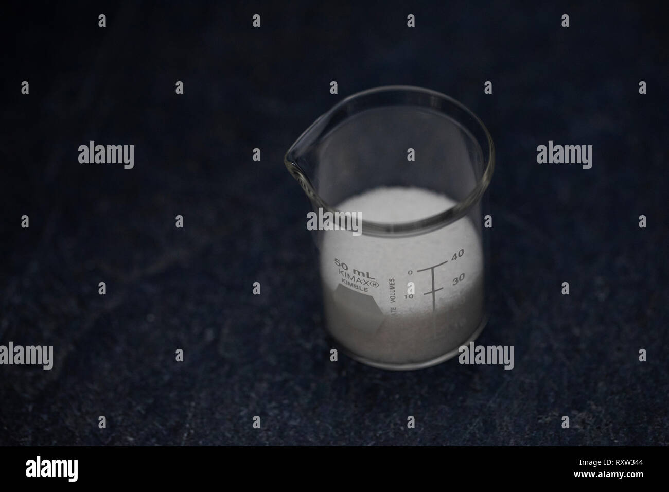 Sugar crystals in a beaker on a dark background Stock Photo - Alamy