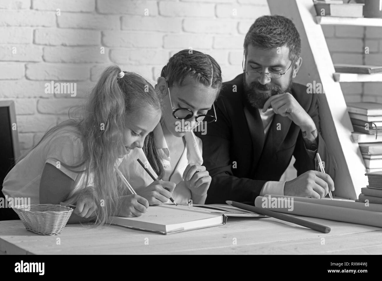father and daughters writing white home schooling. Father helps ...