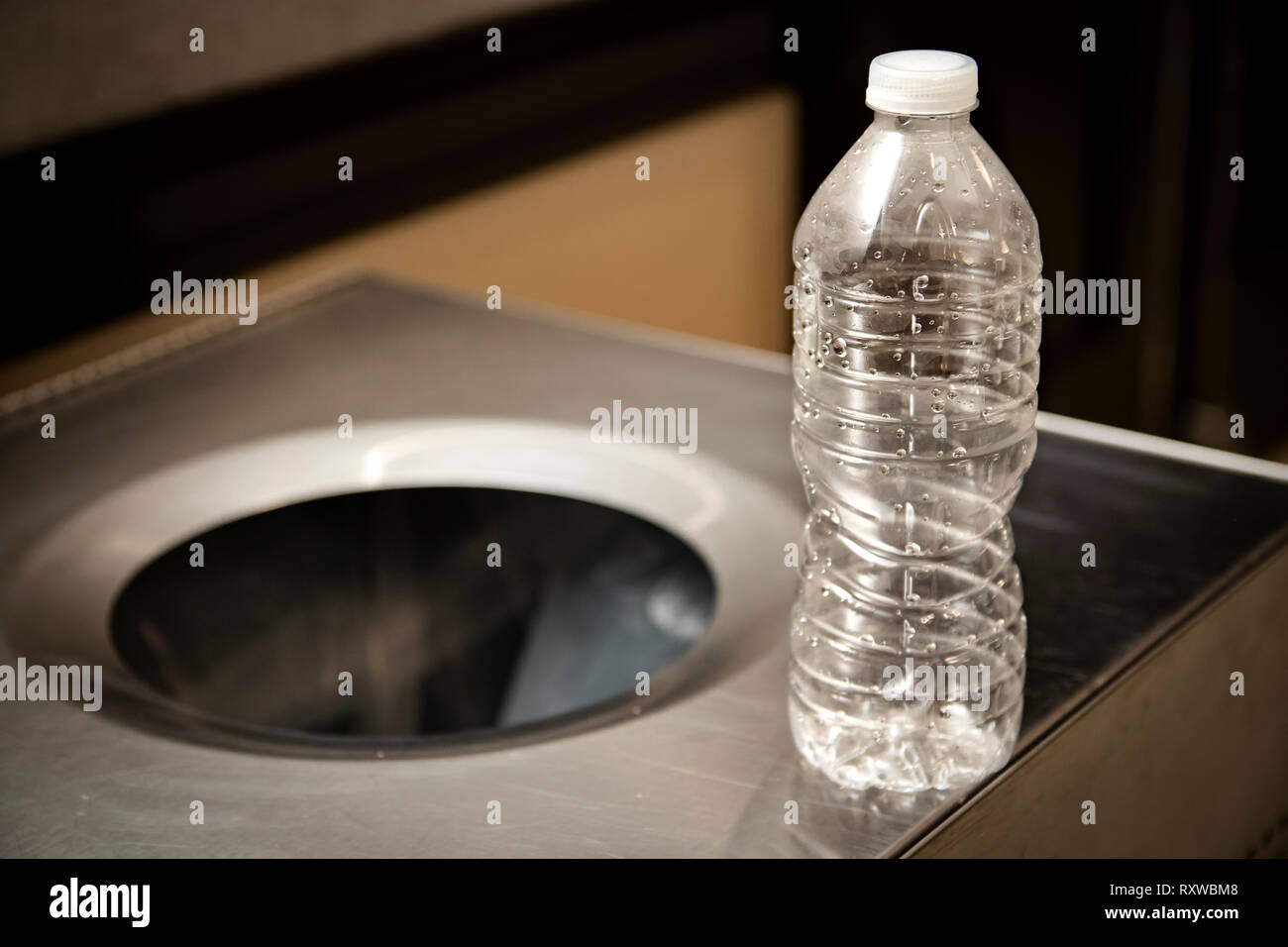 Singe use disposable plastic water bottle next to trash or recycling ...