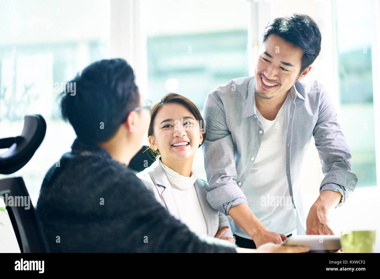 three young asian teammates working together having a pleasant business ...