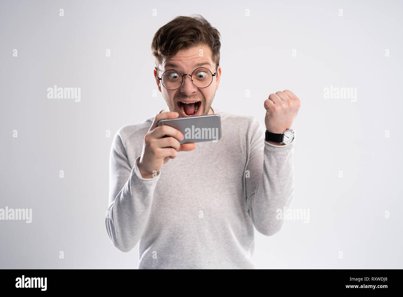 Happy man holding smartphone and celebrating his success over white ...
