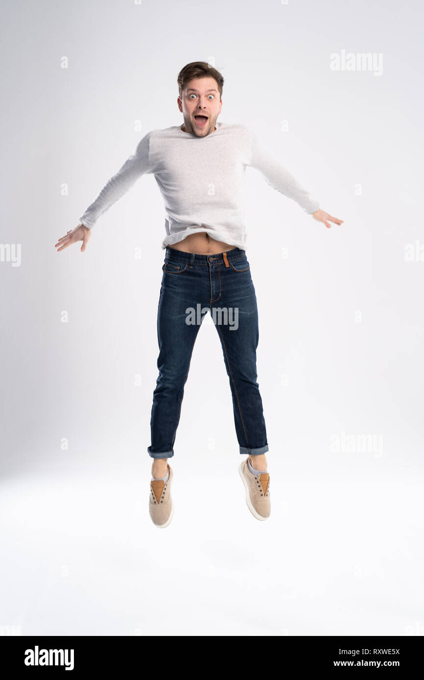 Full-length photo of funny man 30s in casual t-shirt and jeans jumping ...