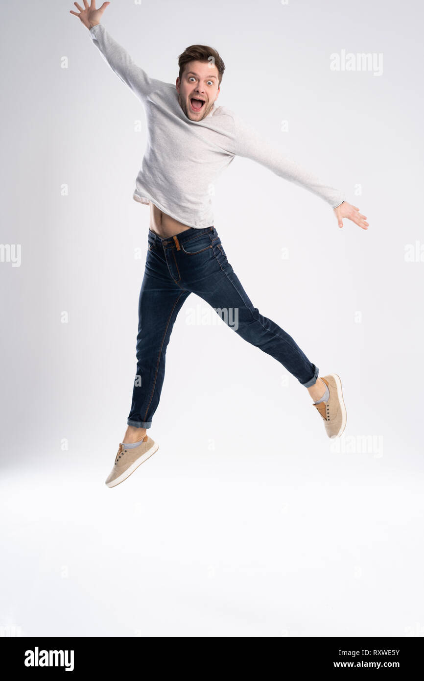 Full-length photo of funny man 30s in casual t-shirt and jeans jumping ...