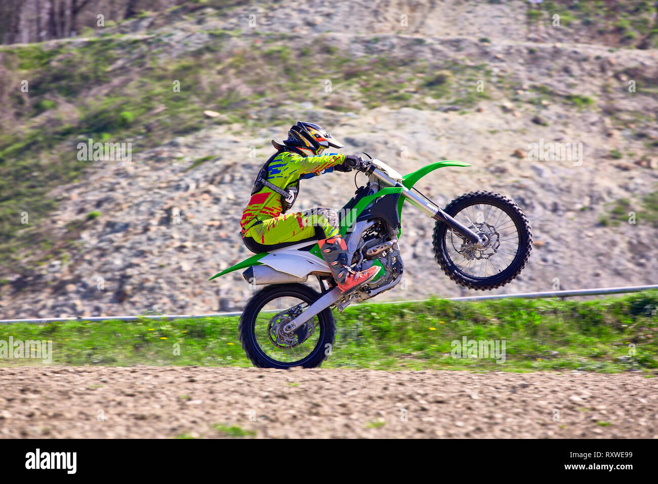 biker on motorcycle stunts while driving on the rear wheel side view ...