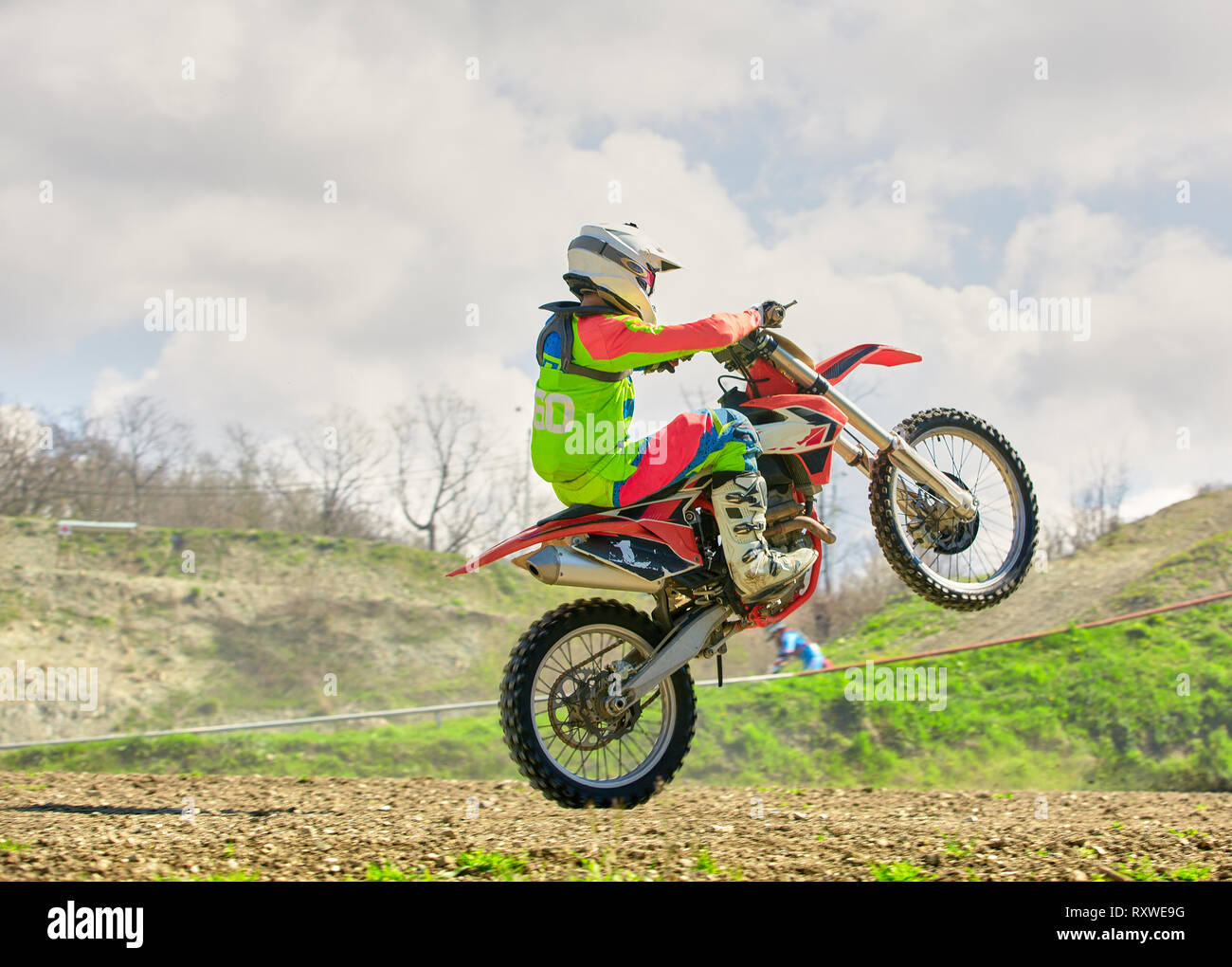 biker on motorcycle stunts while driving on the rear wheel side view ...