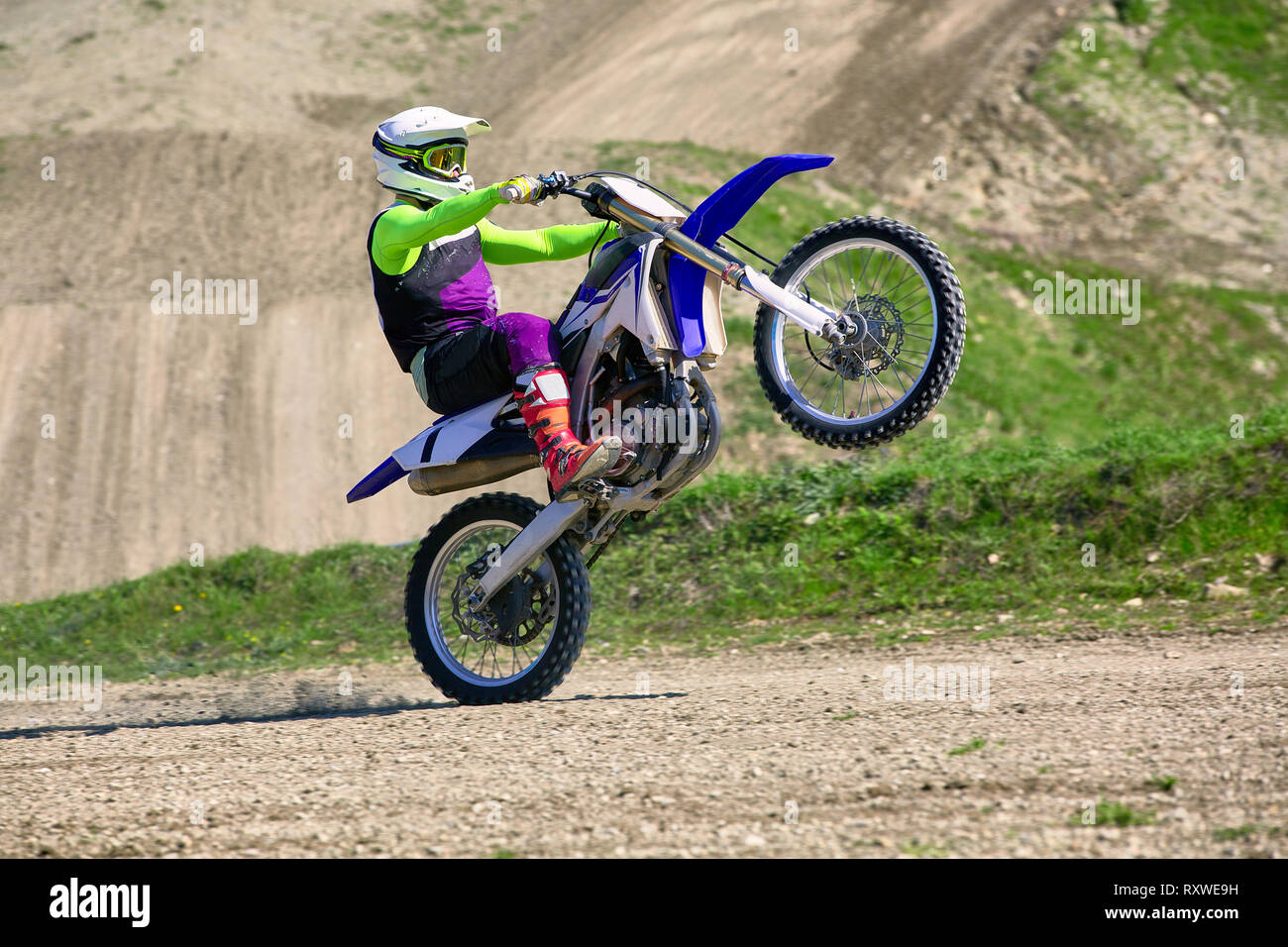 biker on motorcycle stunts while driving on the rear wheel side view ...