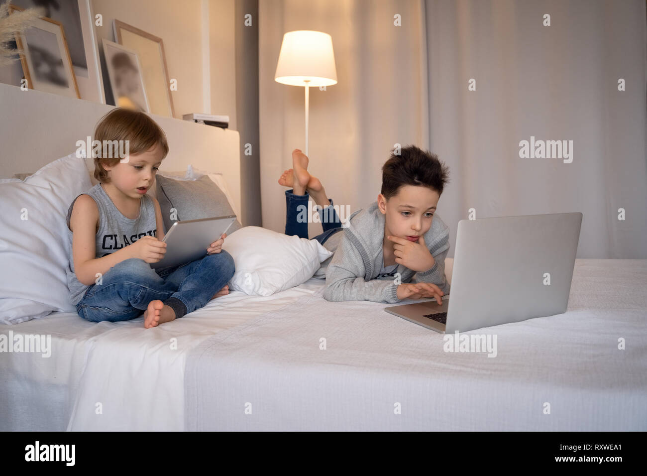 Two children, boys in parents' bed at morning with laptop and tablet ...
