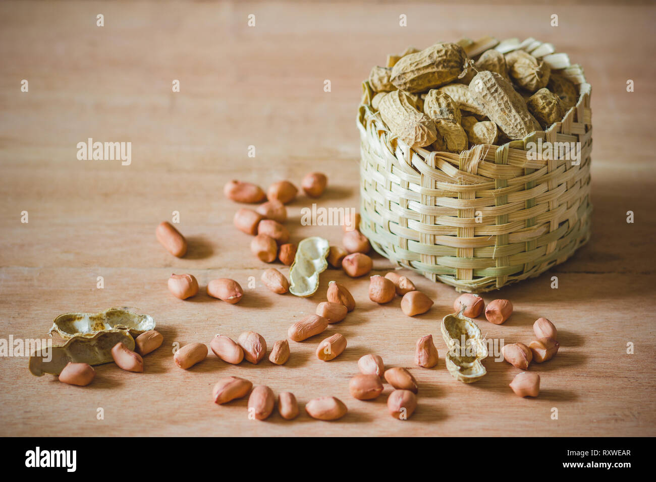 Peanuts in mini bamboo basket on brown wood background Stock Photo - Alamy