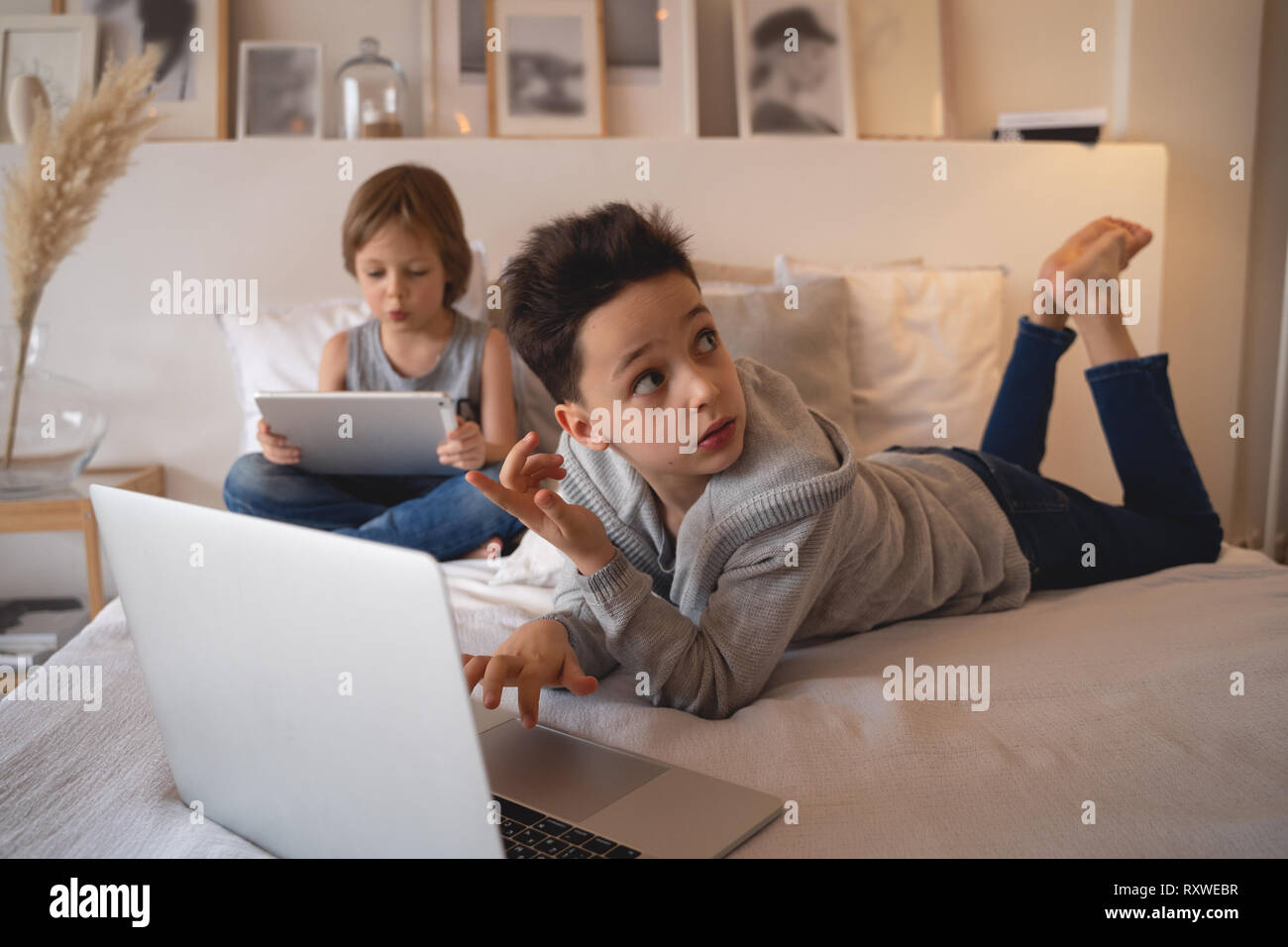 Two children, boys in parents' bed at morning with laptop and tablet ...