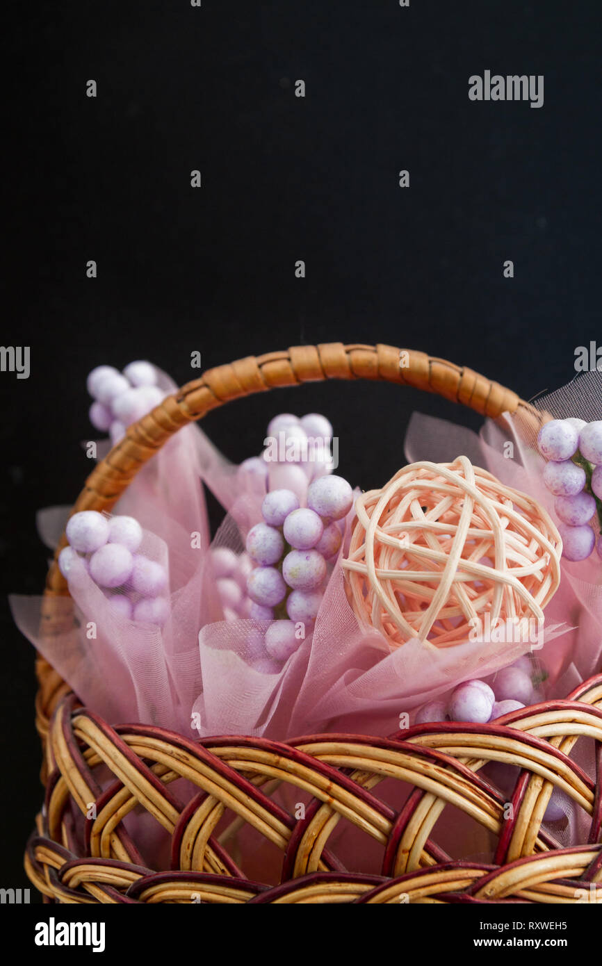 Spring straw basket with pink decorations and roundels on black ...
