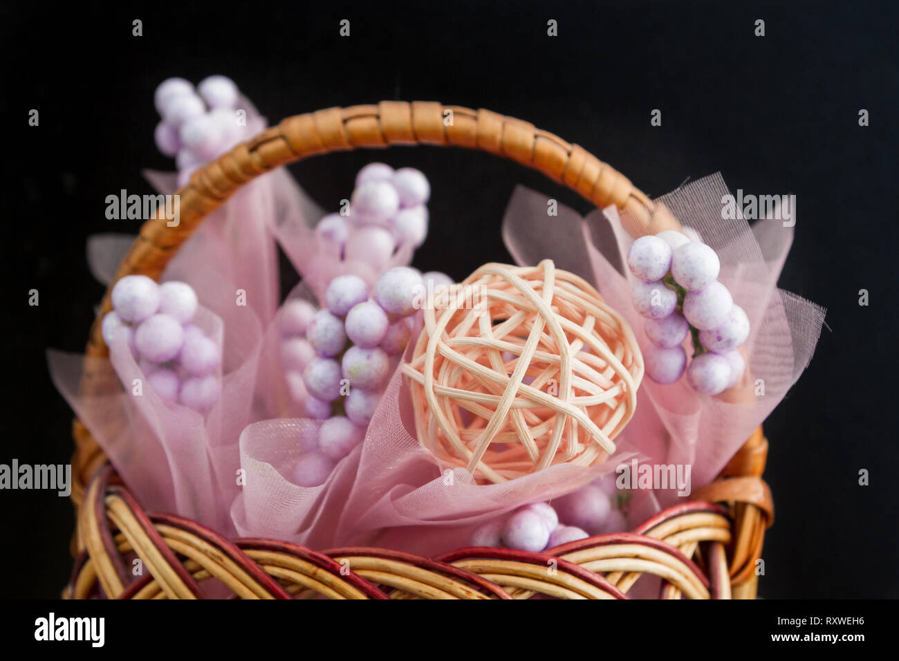 Spring straw basket with pink decorations and roundels on black ...