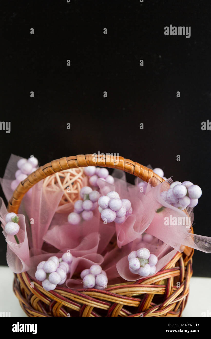 Spring straw basket with pink decorations and roundels on black ...