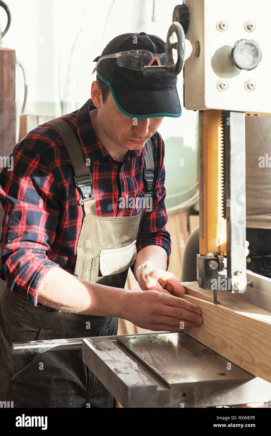 Construction worker cutting wooden board Stock Photo - Alamy