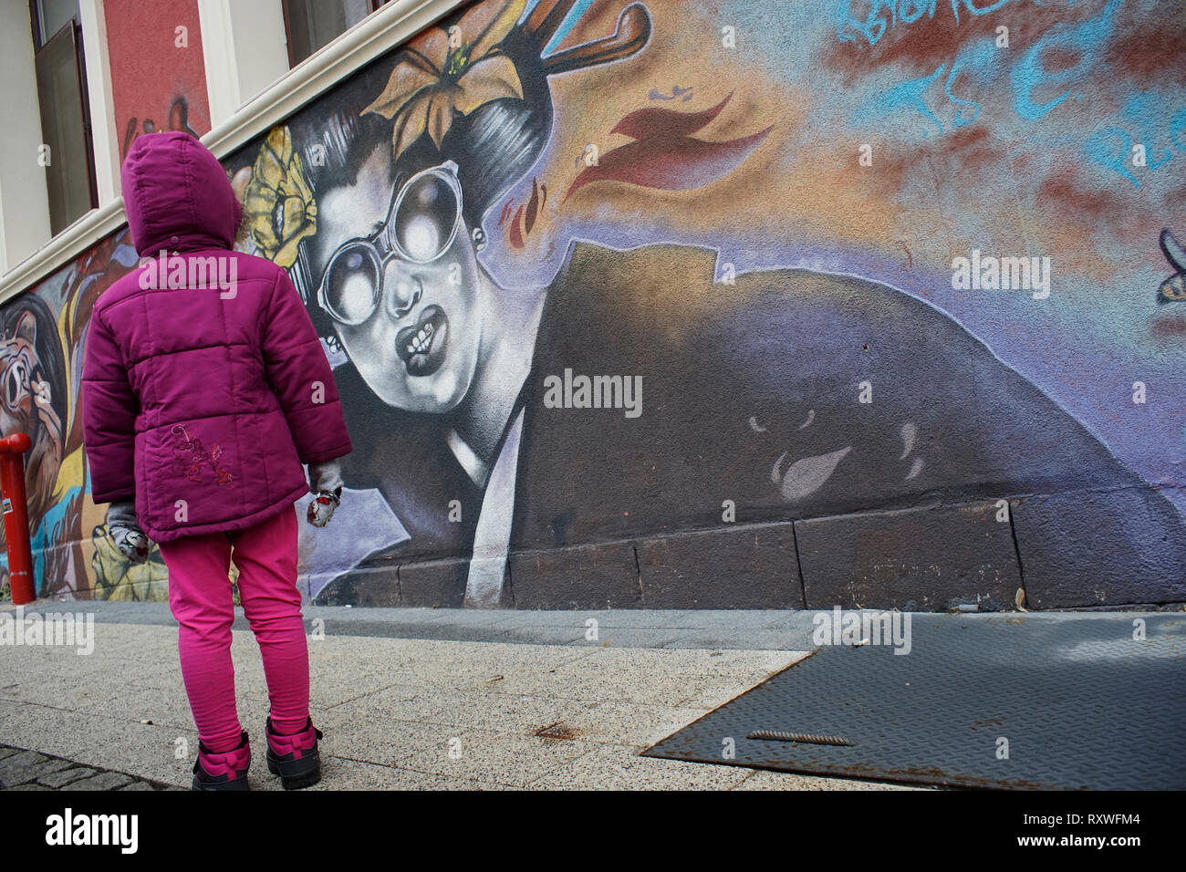 Child is standing in front of a graffiti painted wall Stock Photo - Alamy