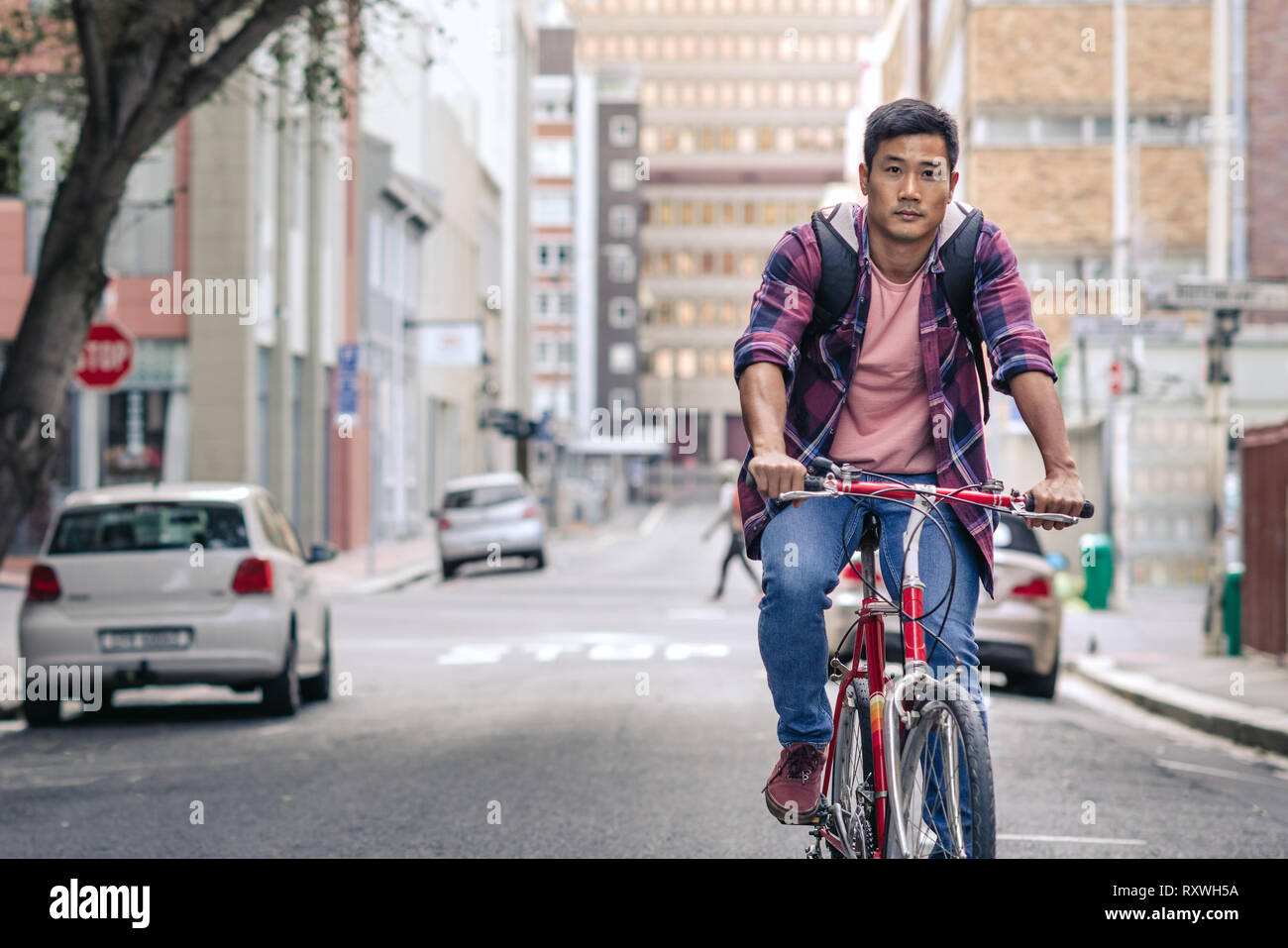 Young Asian man riding his bike through city streets Stock Photo - Alamy