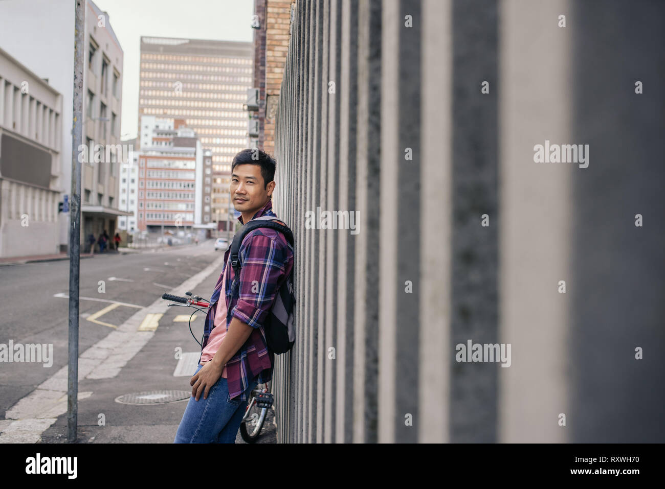 Young man leaning against a city wall with his bike Stock Photo - Alamy