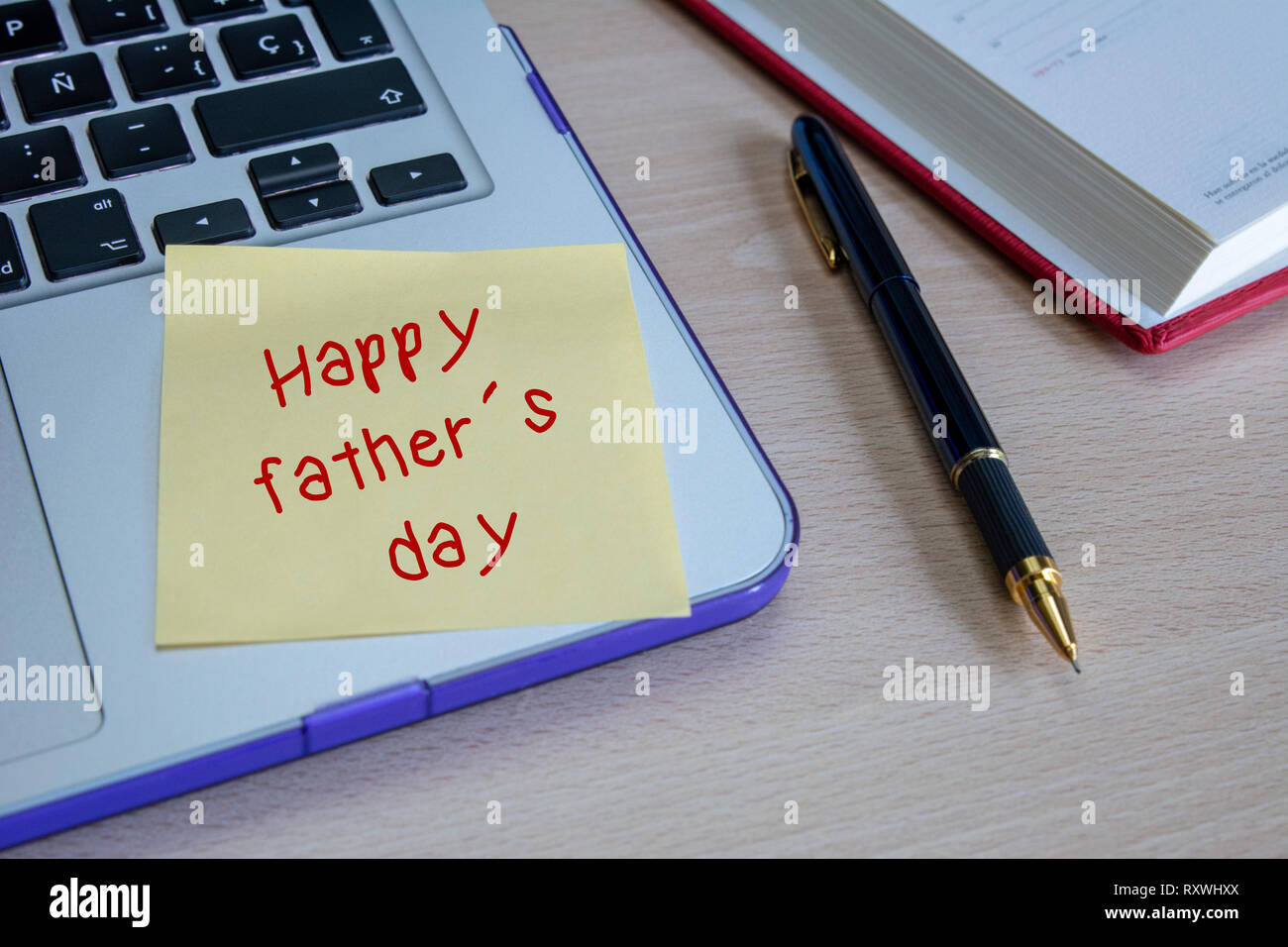 Laptop and stick note with happy fathers day written on wooden table ...