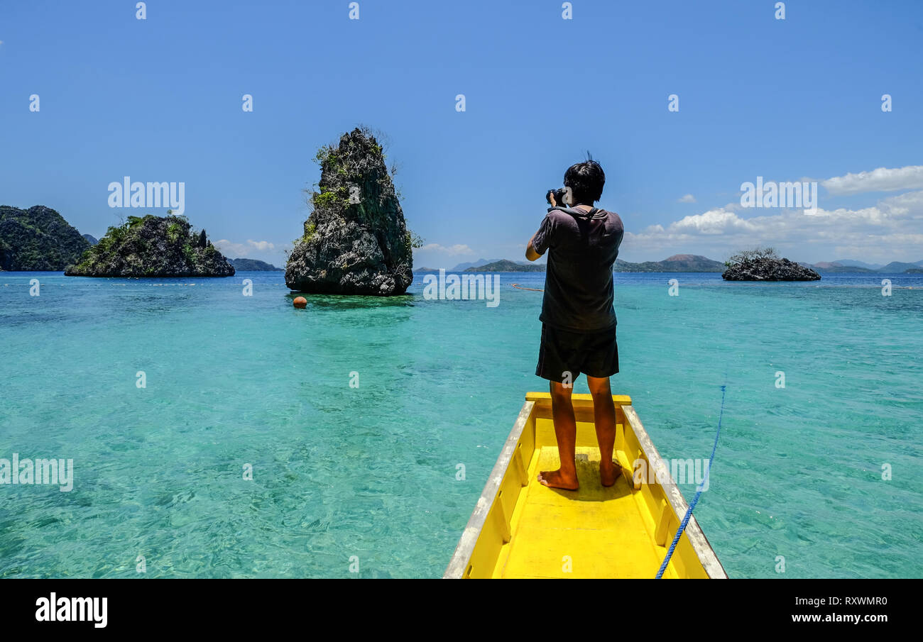 A young man standing on wooden boat and looking at the seascape of ...