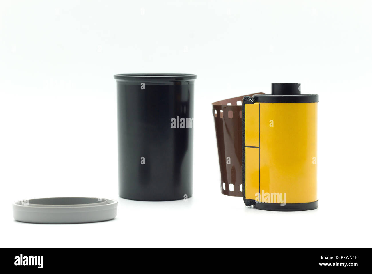 Black film bottle with gray bottle cap and yellow roll film on a white ...