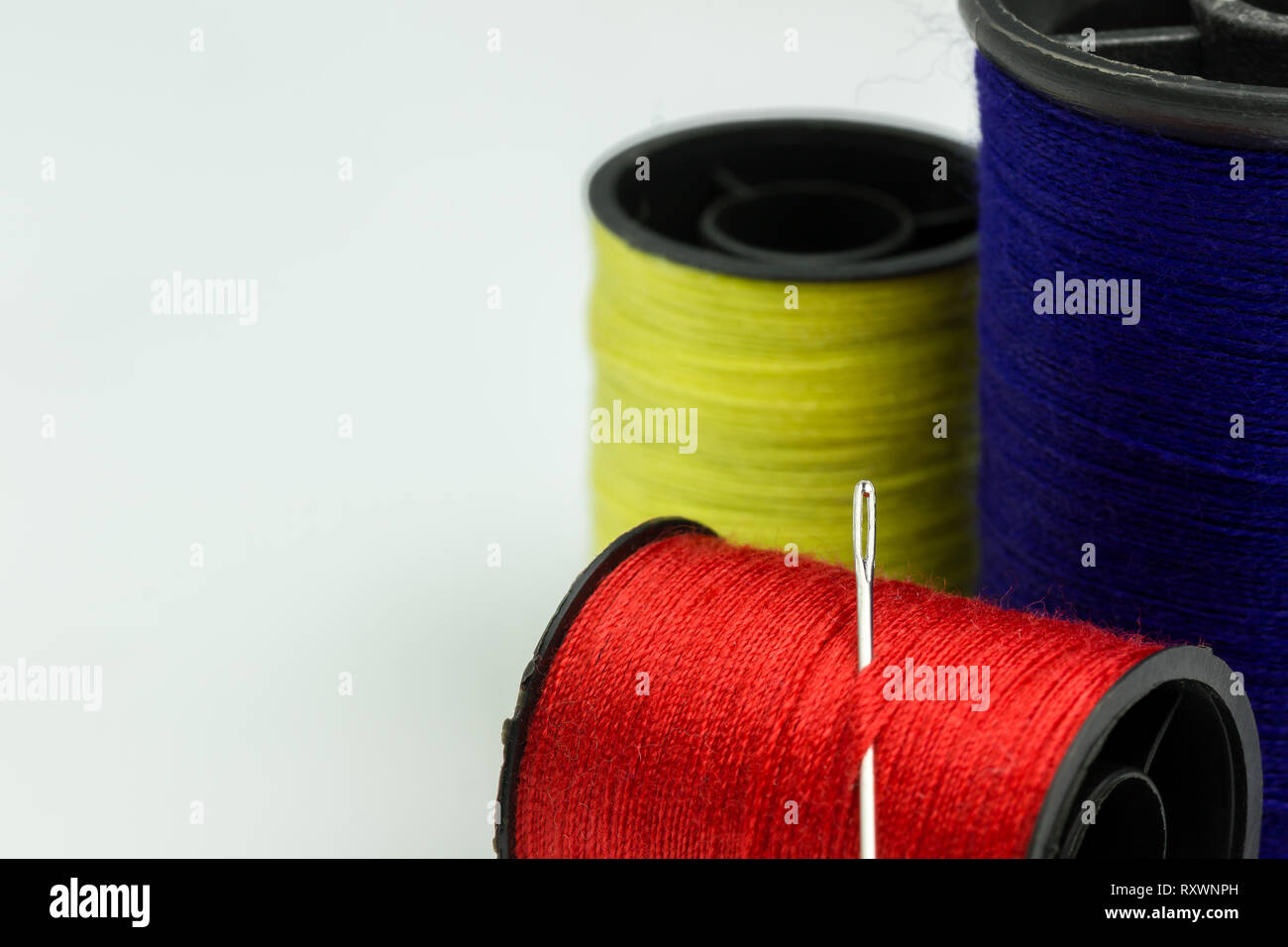 Close up Thread roller Blue, Red, Yellow and Sewing Needles in white ...